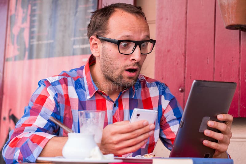 Handsome Young Man Eating Sandwich in Restaurant. he is Holding a Phone ...
