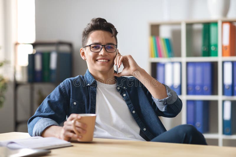 Handsome Young Man Enjoying Phone Conversation during Coffee Break in ... Handsome Young Man Enjoying Phone Conversation during Coffee Break in ...