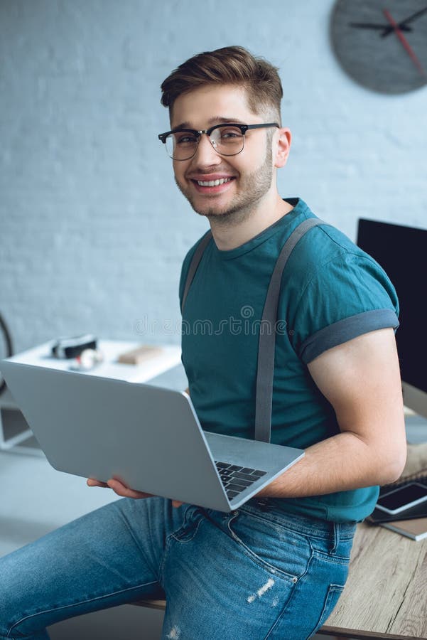 Handsome Young Man in Eyeglasses Holding Laptop and Smiling Stock Photo ...