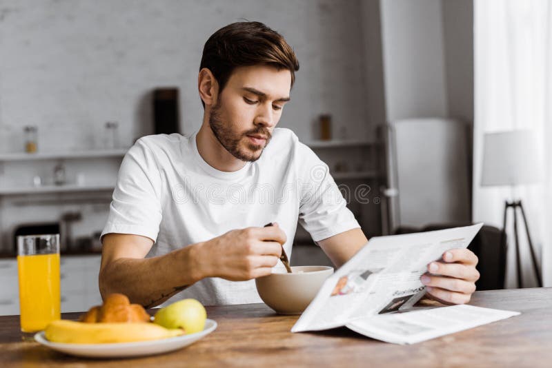 Handsome Young Man Having Breakfast and Reading Newspaper Stock Photo ...