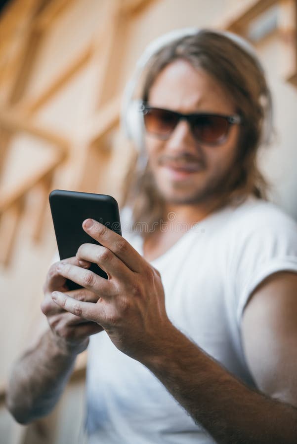 Handsome Young Man In Headphones And Sunglasses Using Smartphone Stock