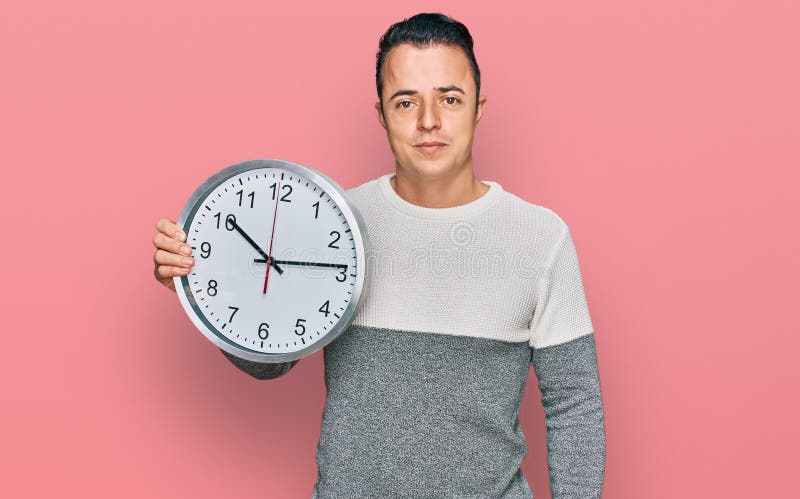 Handsome Young Man Holding Big Clock Thinking Attitude and Sober ...