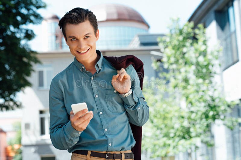 Handsome Young Man Holding Smartphone and Smiling Stock Photo - Image ...