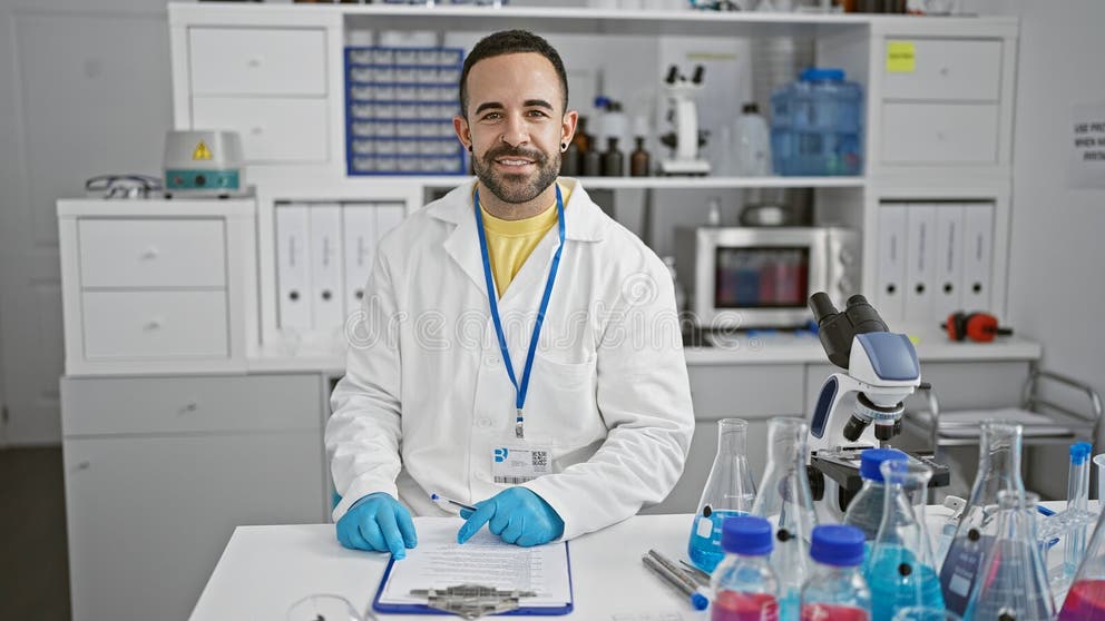 Handsome Young Man in Labcoat Writing Notes in a Clinical Laboratory ...