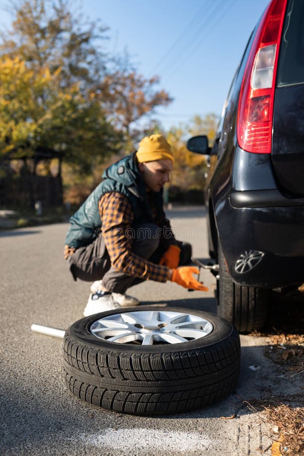 Handsome Young Man Lifting the Car on the Jack for Changing Flat Tire ...