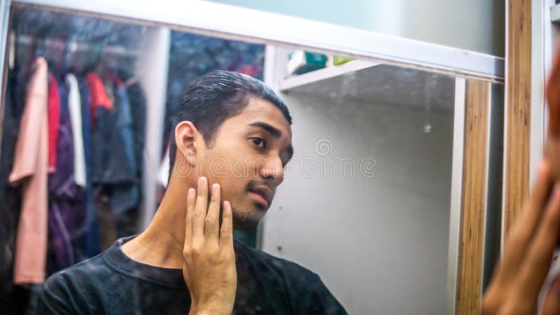 Handsome Young Man Looking at Himself at the Mirror while Combing His ... Handsome Young Man Looking at Himself at the Mirror while Combing His ...