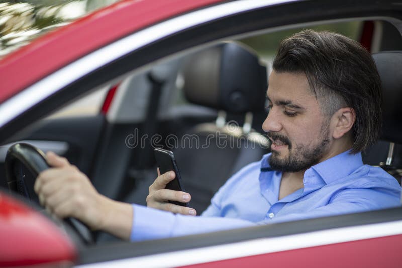 Handsome Young Man Looking at the Phone while Driving Stock Photo ...