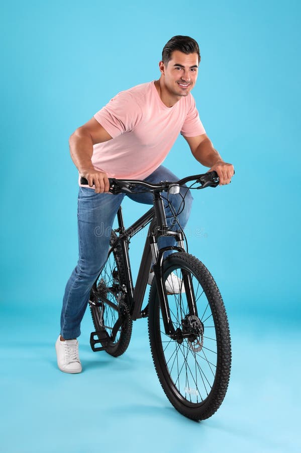 Handsome Young Man with Bicycle on Light Blue Background Stock Photo ...