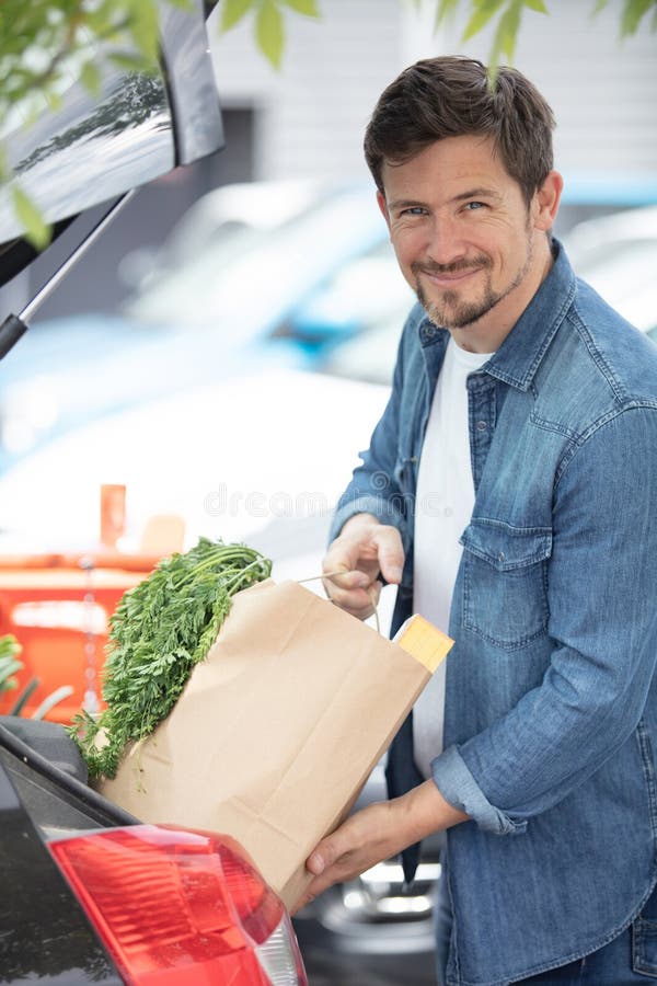 Handsome Young Man Packing Groceries into Car Trunk Outdoors Stock ...