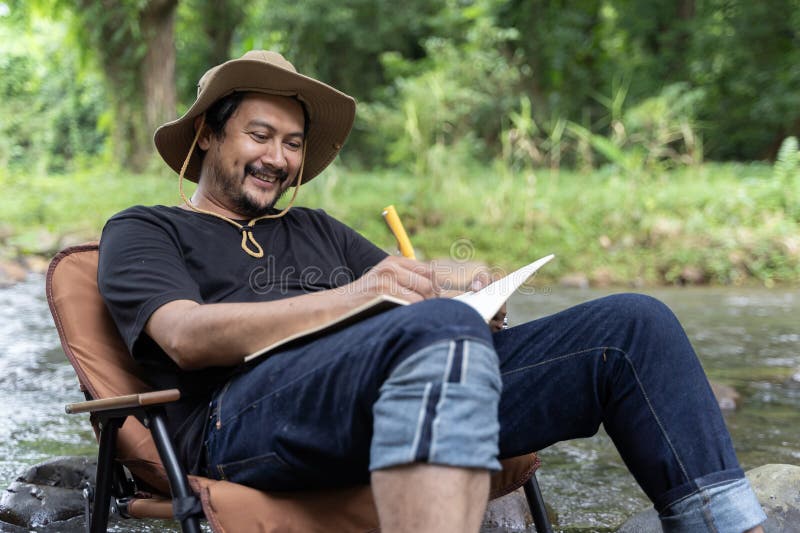 Handsome Young Man Sitting in a Chair Immersed in Water, Writing, Doing ...