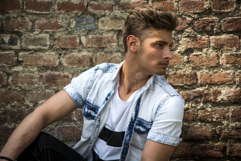 Handsome Young Man Sitting Outside in Front of Brick Wall Stock Image ...