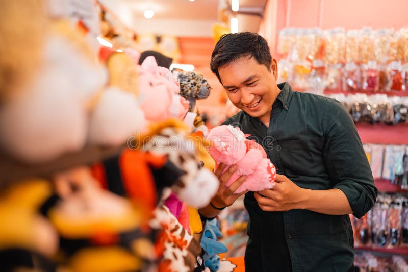 Handsome Young Man Smiles at a Doll while Choosing for Gift Stock Image ...