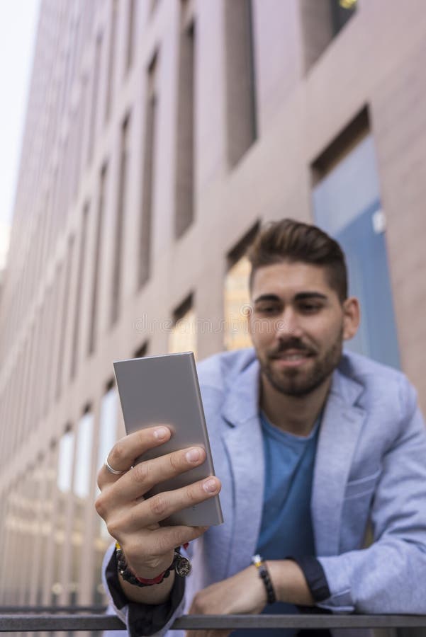 Handsome Young Man Smiling when he is Using His Mobile Phone Stock ...