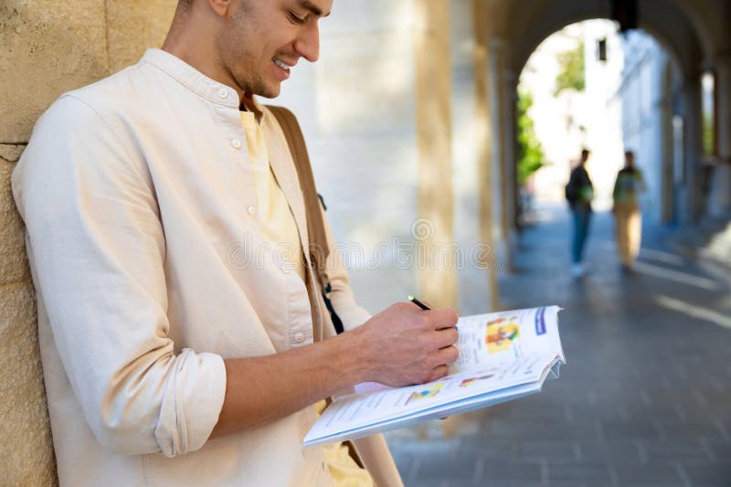 Handsome Young Man Standing Near the Wall with a Textbook in Hands ...