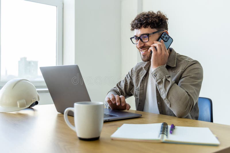 Handsome Young Man Talking on Smart Phone and Using Computer while ...