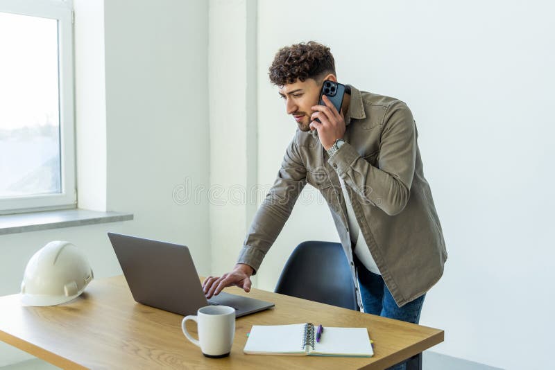 Handsome Young Man Talking on Smart Phone and Using Computer while ...
