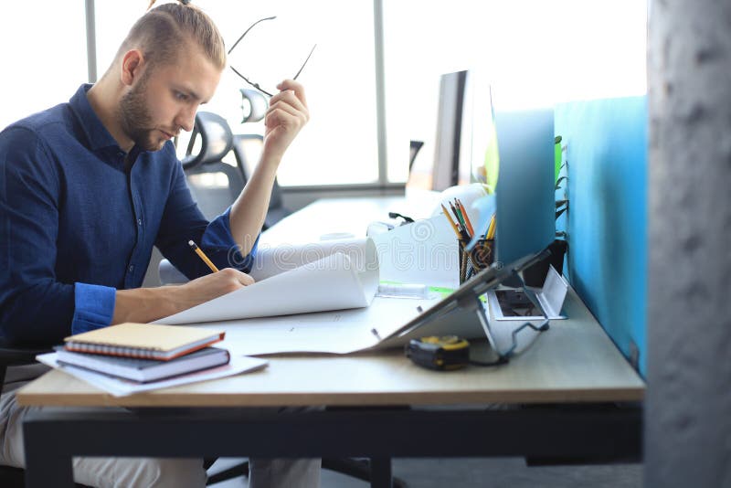 Handsome Young Man Using Blueprint while Working in the Creative ...