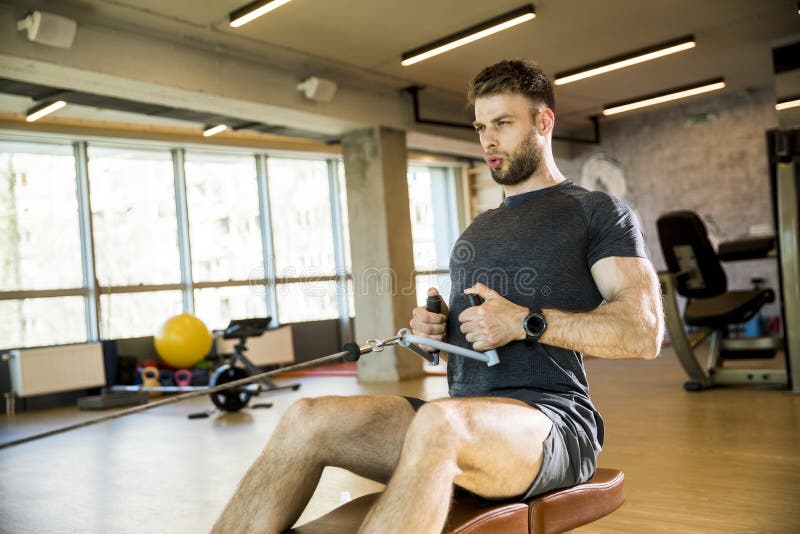 Young Man Using Seated Row Machine in the Gym Stock Photo - Image of ...