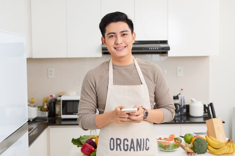 Handsome Young Man Using Smartphone while Cooking Stock Image - Image ...