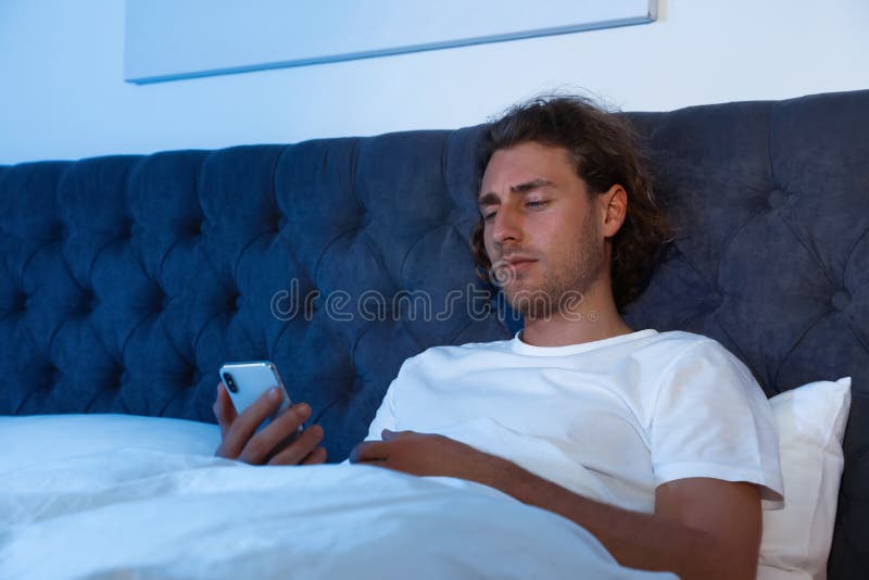 Handsome Young Man Using Smartphone at Night. Bedtime Stock Image ...