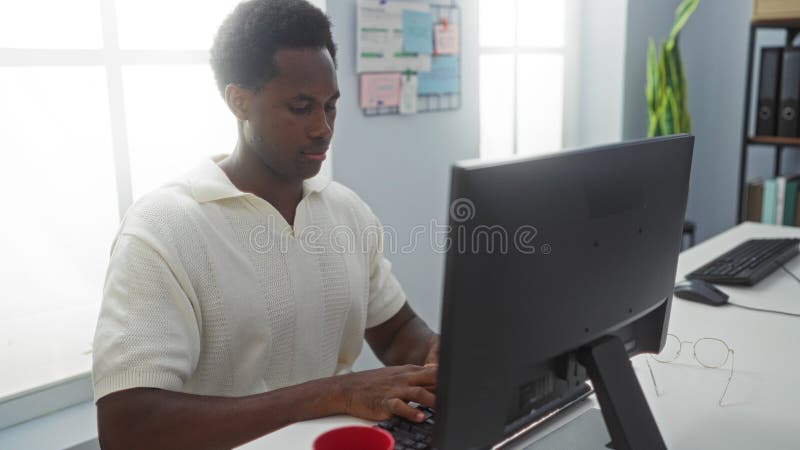 Handsome Young Man Working at a Computer in an Office Setting while ...