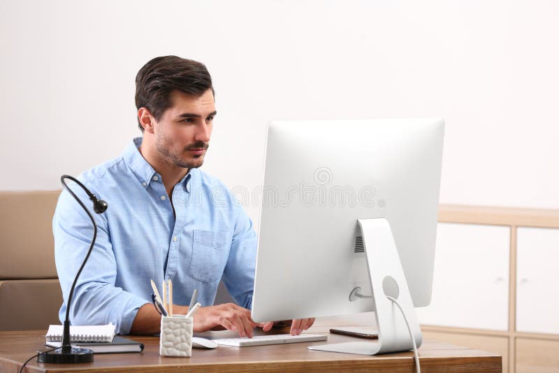 Handsome Young Man with Computer at Table in Office Stock Image - Image ...