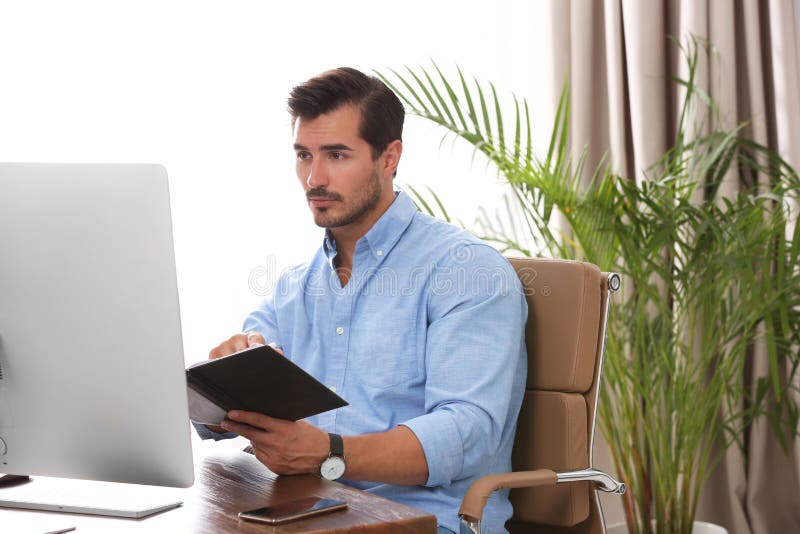 Handsome Young Man Working with and Computer at Table in Office Stock ...