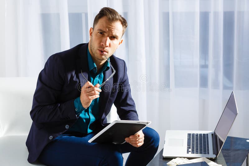 Handsome Young Man Working while Sitting on the Couch in Office Stock ...