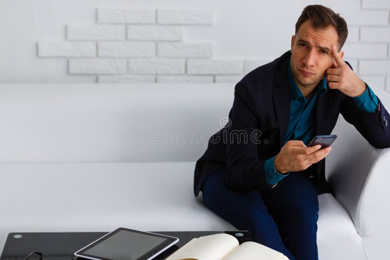 Handsome Young Man Working while Sitting on the Couch in Office Stock ...