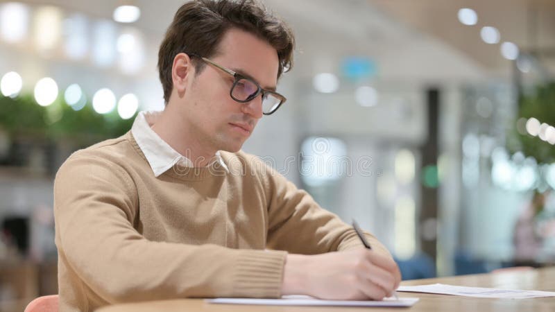 Handsome Young Man Writing on Paper in Office Stock Image - Image of ...