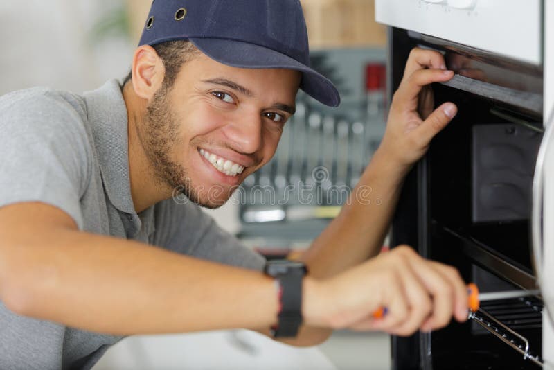 Handsome Young Repairman Fixing Oven with Screwdriver Stock Photo ...