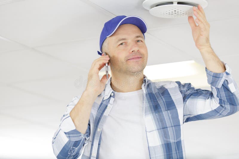 Handyman Installing Smoke Detector Calling with Phone Stock Photo ... Handyman Installing Smoke Detector Calling with Phone Stock Photo ...