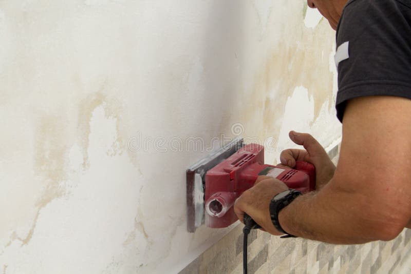 Handyman Removing Plaster and Mold from a Wall with a Sanding Machine ...