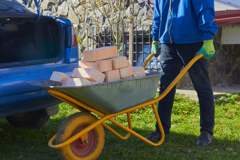 Handyman with a Wheelbarrow of Bricks, a Builder Steals a Brick into ...