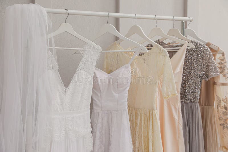 Hangers with Different Beautiful Dresses and Wedding Veil on Rack in ...