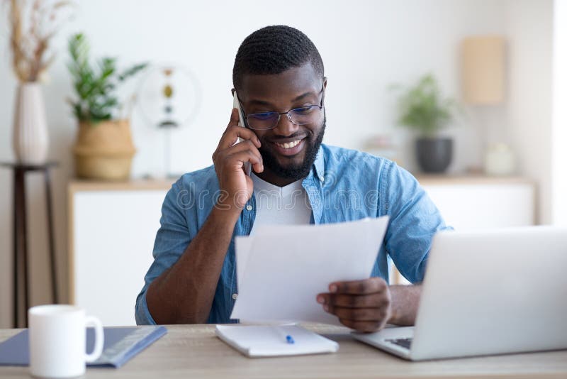 Happy African Entrepreneur Talking To Client on the Phone while Holding ...