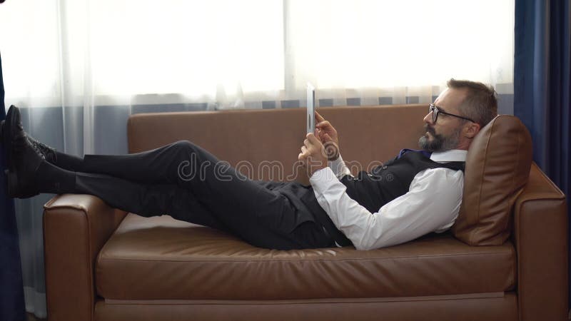 Happy Bearded Businessman Take a Break Lying Down on Sofa Using Digital ...