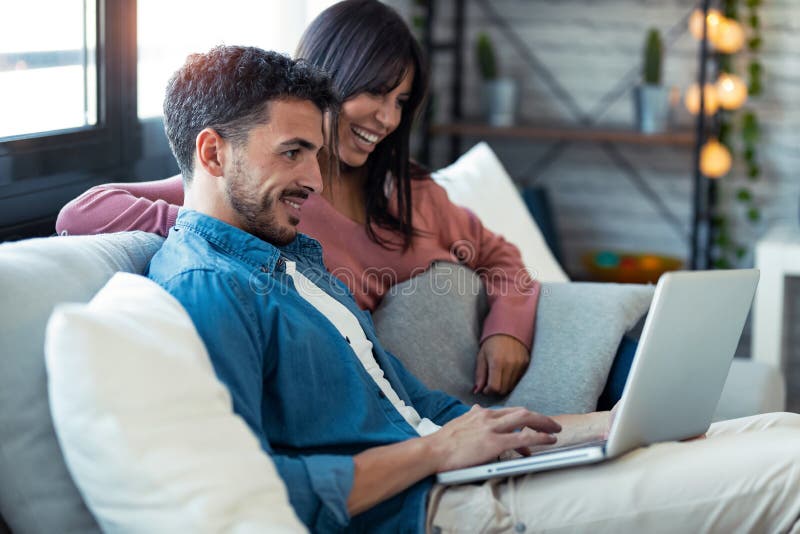 Happy Beautiful Couple Using Computer while Sitting on the Couch at ...