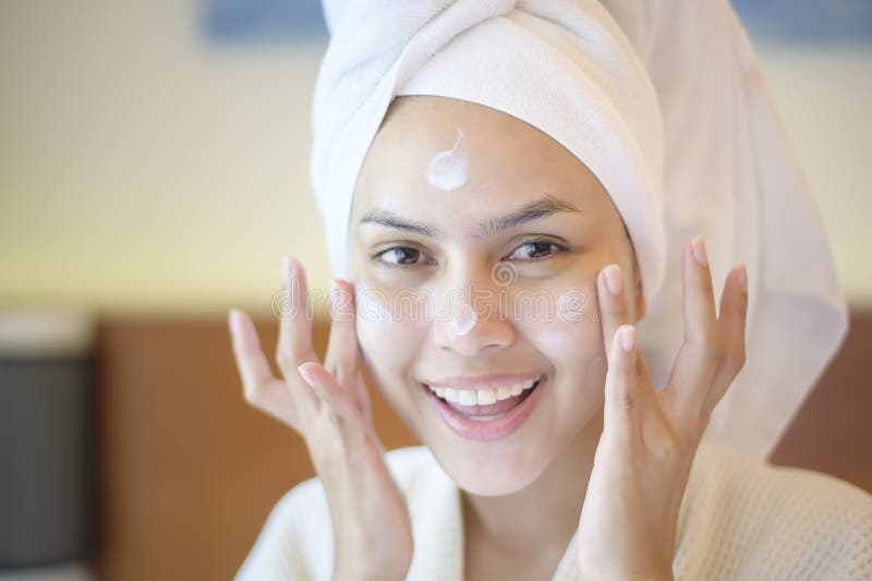 Happy Beautiful Woman In White Bathrobe Applying Moisturizing Cream On