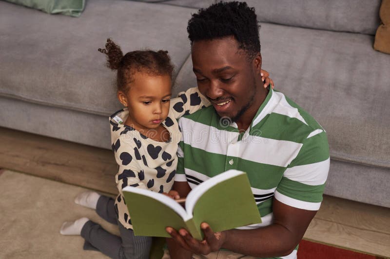 Happy Black Father and Daughter Reading Book Together at Home Stock ...