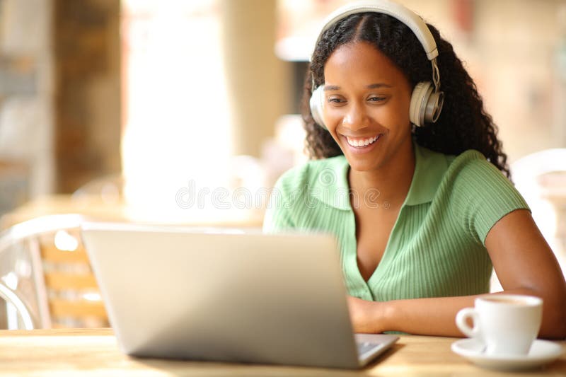 Happy Black Woman Using Laptop and Headphone in a Bar Stock Photo ...