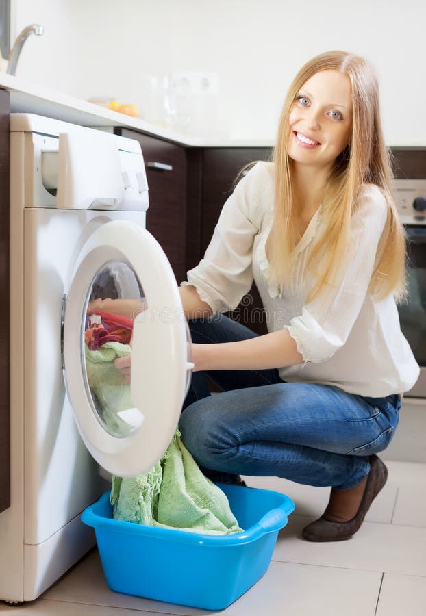 Happy Blonde Woman Loading Clothes into the Washing Machine Stock Image ...