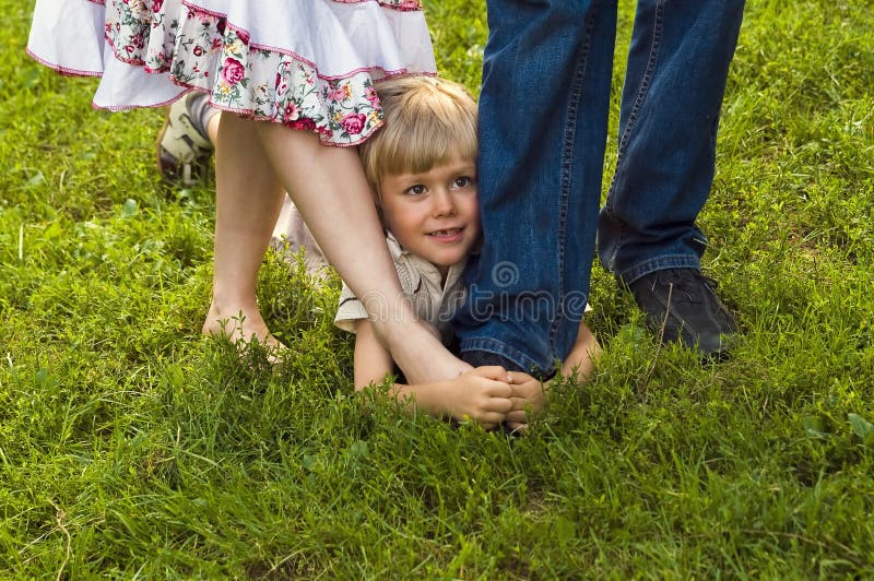 Happy Boy Hiding in Parents Legs Stock Photo - Image of color, hode ...
