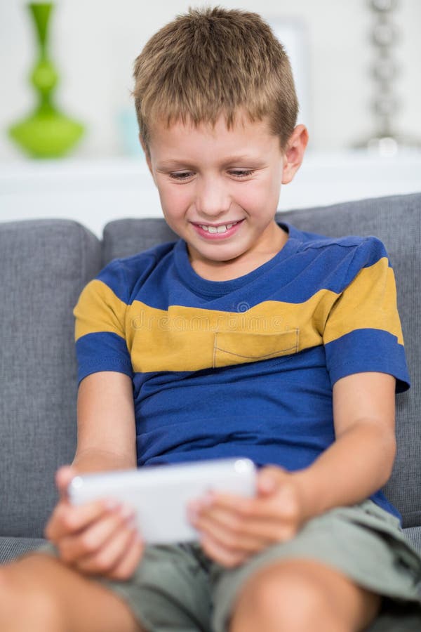 Happy Boy Sitting on Sofa and Using Mobile Phone in Living Room Stock ...