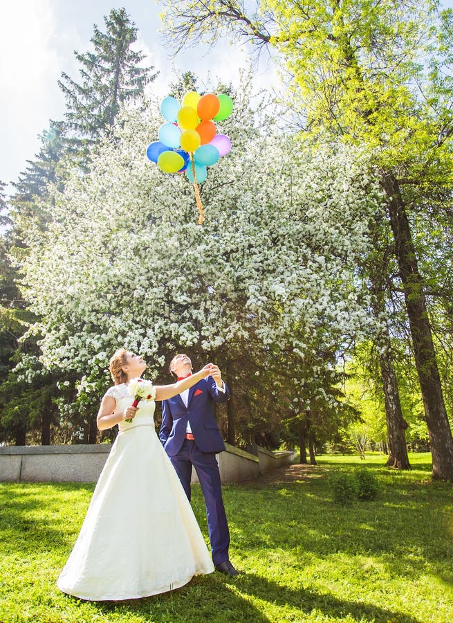 Happy Bride and Groom Walking Together in a Spring Park with Balloons ...