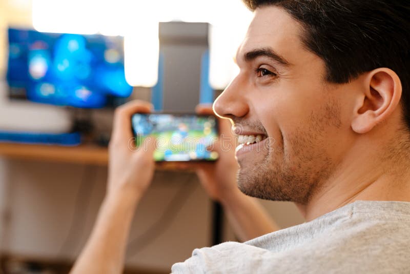 Happy Brunette Guy Playing Video Game on His Mobile Phone Stock Image ...