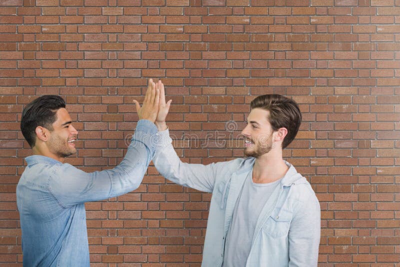Happy Business Men Doing a High Five Against Brick Wall Stock Photo ...