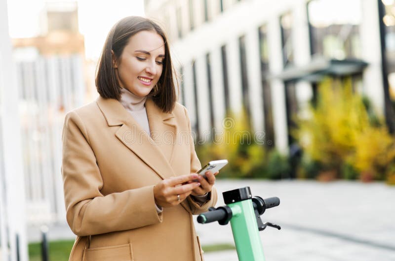 Happy Business Woman Using Smartphone App For Renting E Scooter Stock