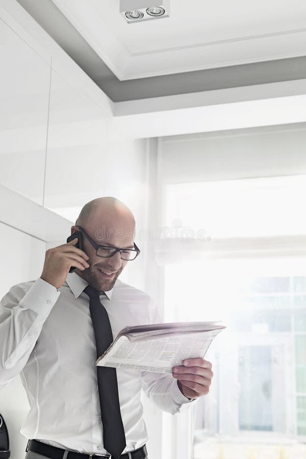 Happy Businessman on Call while Reading Newspaper at Home Stock Image ...