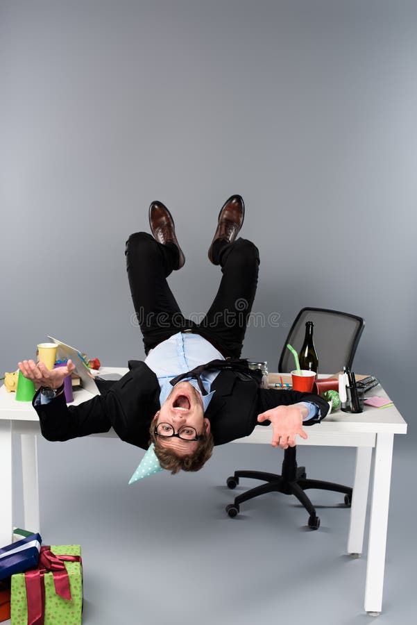 Happy Businessman in Party Cap Lying on Table at Messy Workplace. Stock ...